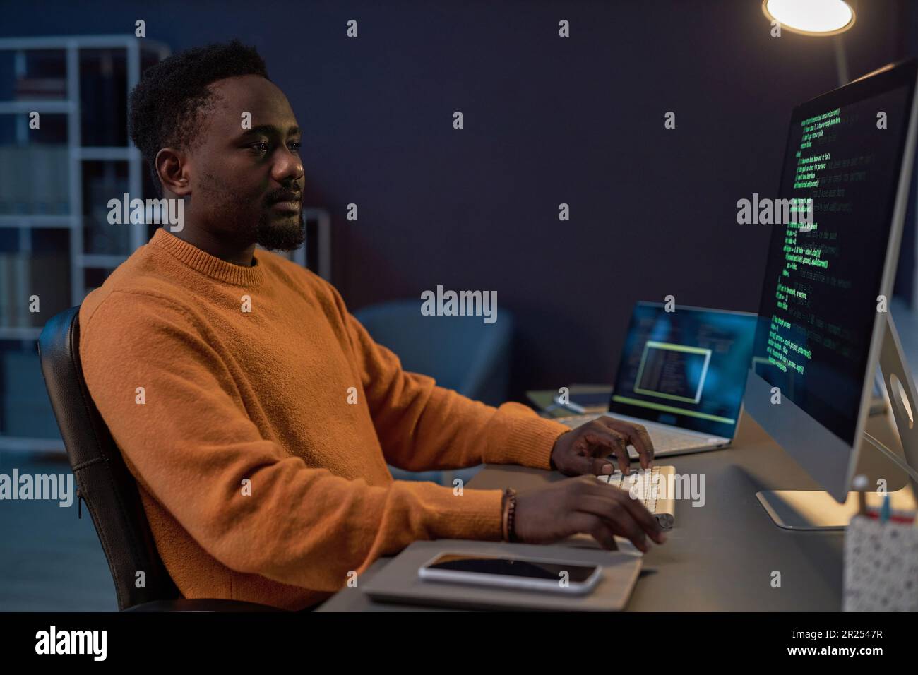 African American developer working with security codes of program on computer sitting at his ...