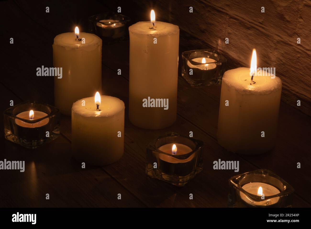 photo burning candles of different sizes on the table Stock Photo - Alamy
