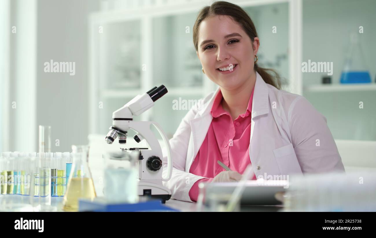 Portraits of smiling woman chemist in front of microscope in laboratory ...