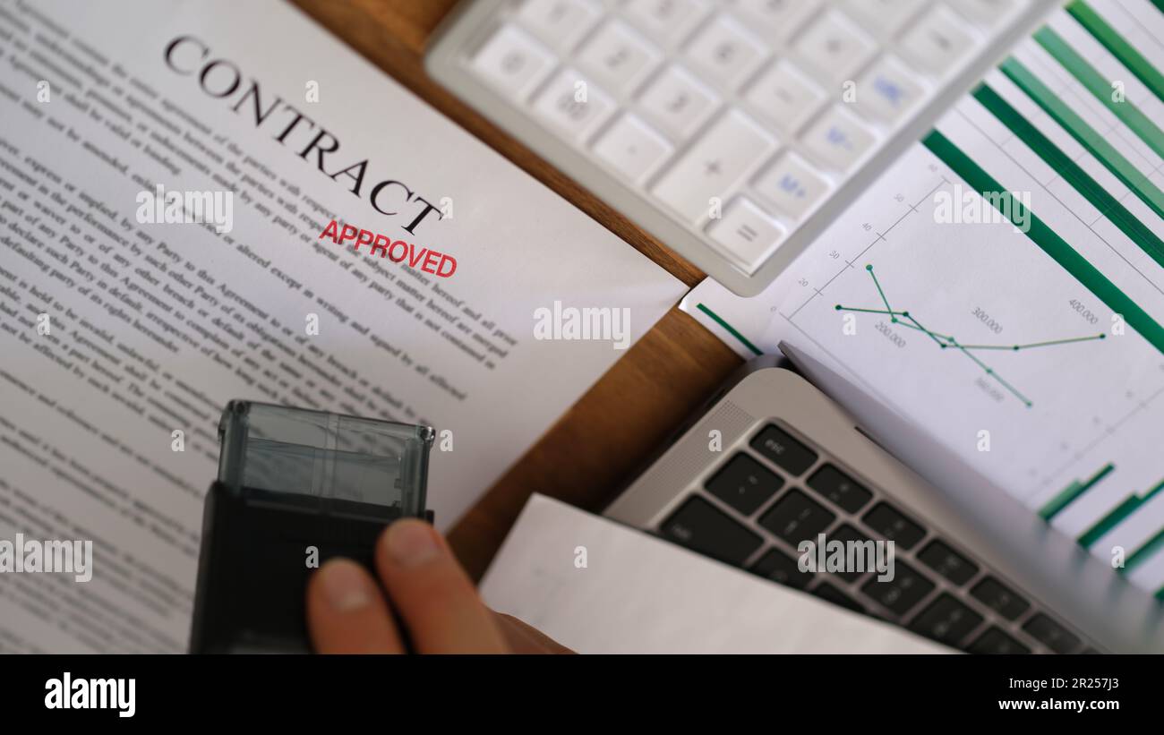 Manager hand putting red stamp approved on contract document closeup ...