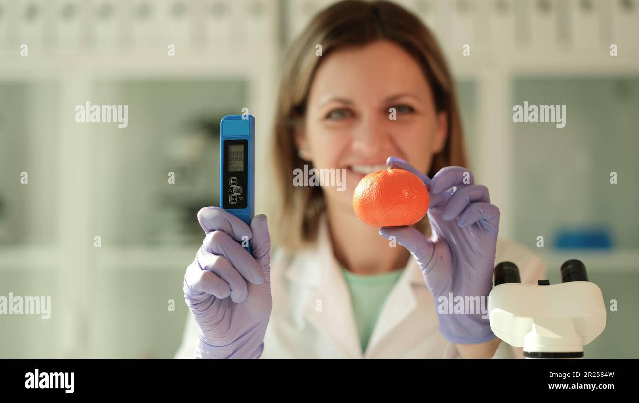 Scientist chemist holding in hands tangerine and device for measuring ...