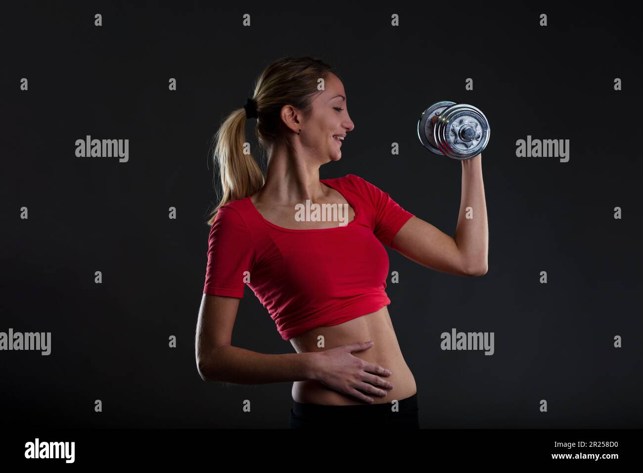 Blonde girl lifting weights in the gym, showcasing her flat stomach ...