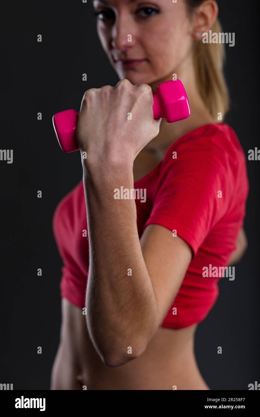 Fitness woman lifting pink weight, blurry in background. Proud blonde ...