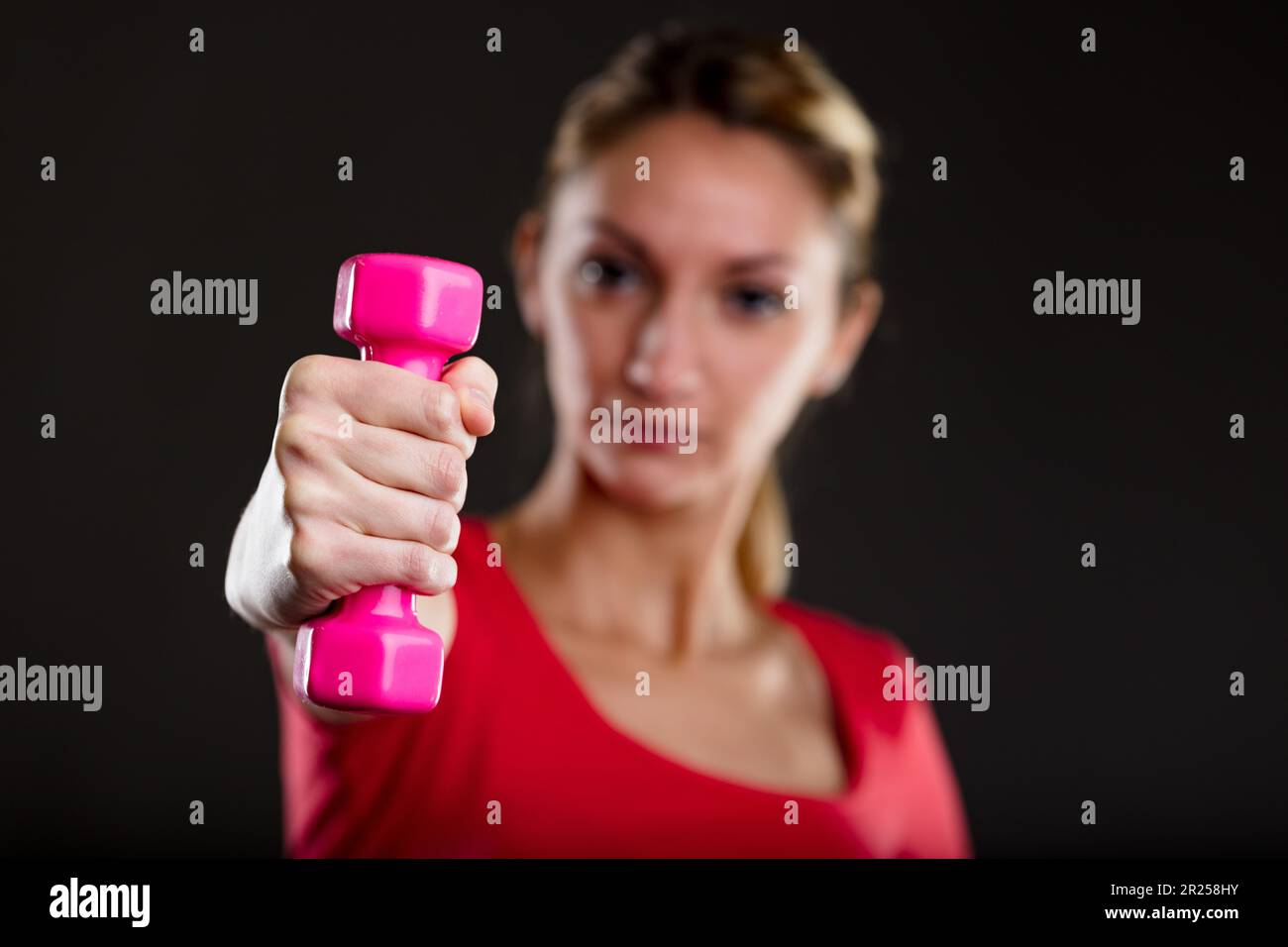 Fitness woman lifting pink weight, blurry in background. Proud blonde ...