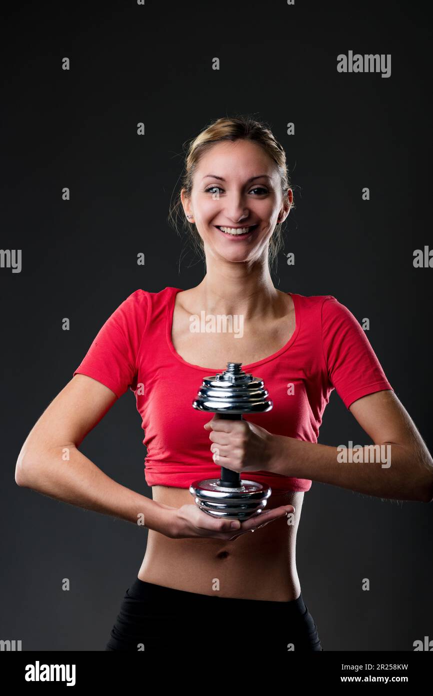 Gym concepts - fitness, stretching, weight lifting. Woman proudly holds ...