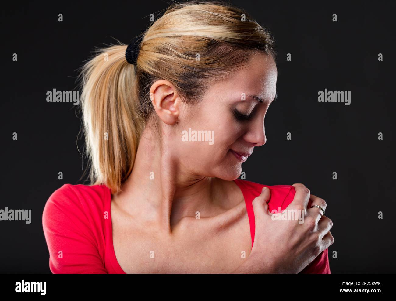 Shoulder pain: woman in red shirt expressing discomfort, grimacing ...