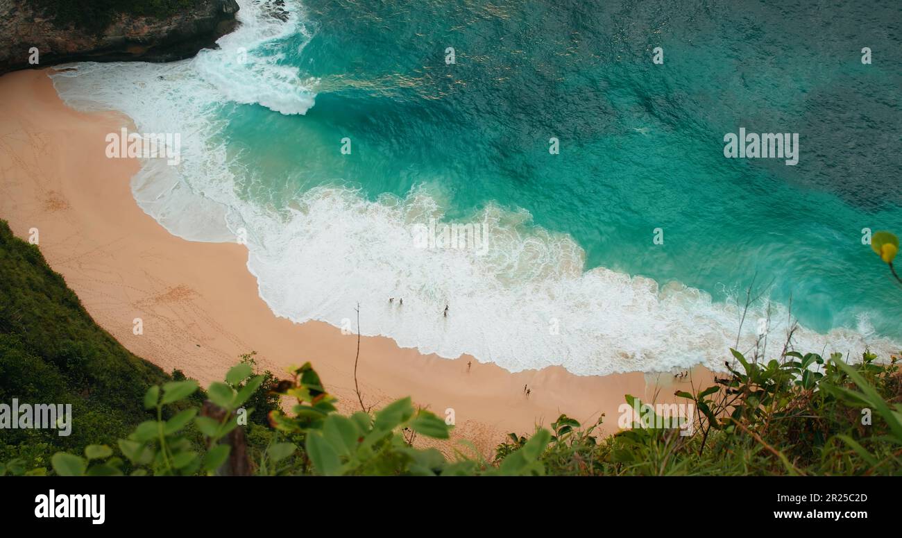 Blue ocean water with giant waves roll on golden sandy Kelingking beach ...