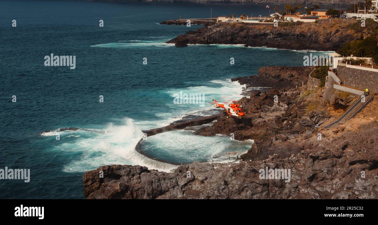 Medical helicopter landing on rocky volcanic shore for rescue operation ...