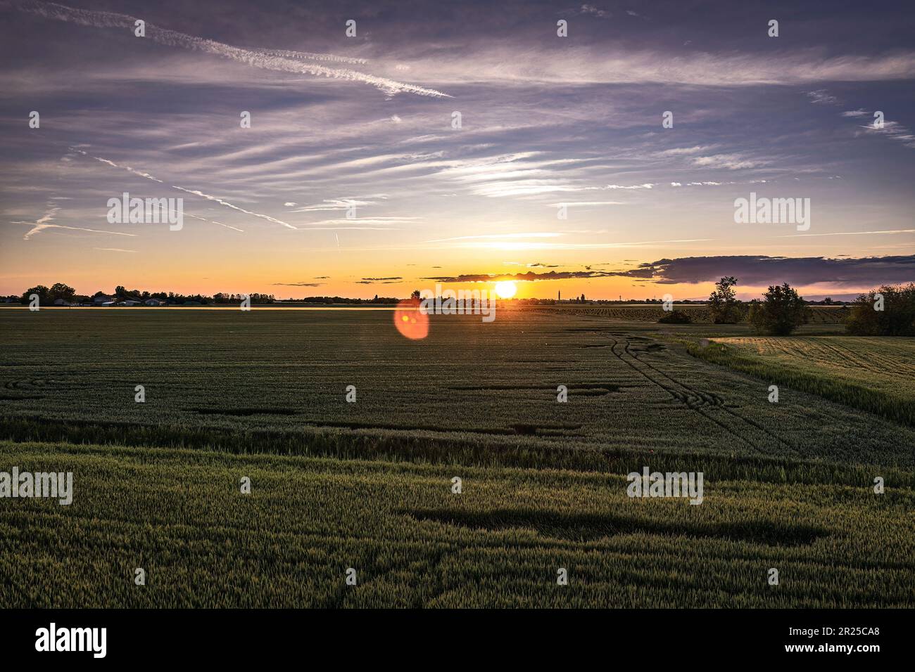 Stunning orange sunset cascades over lush fields in the Po Valley ...