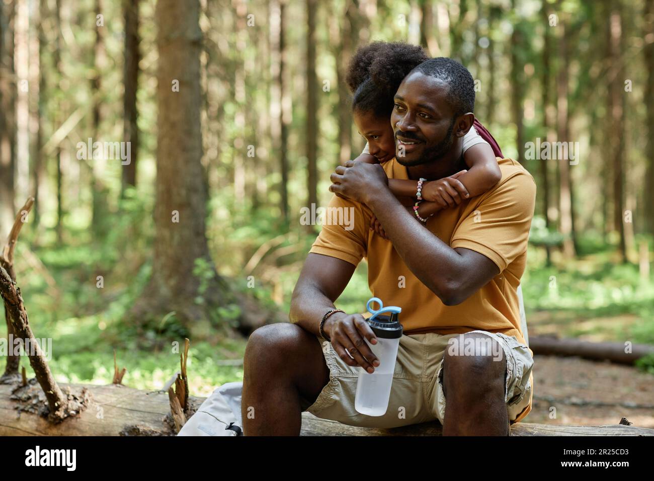 Dad drinking water and resting together with child on log after hiking ...