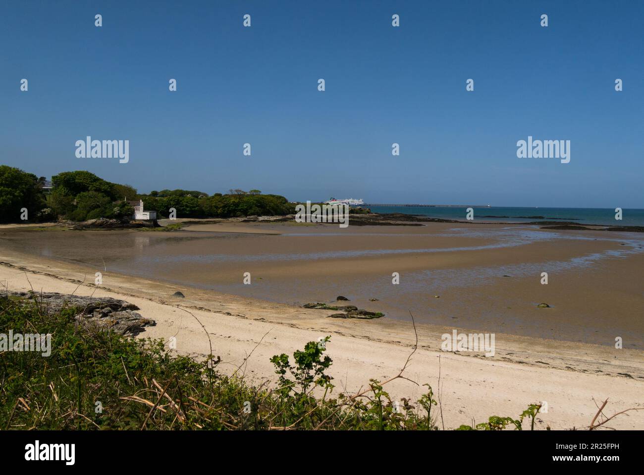 View across sandy beach to Holyhead ferry Port from Penrhos Country ...
