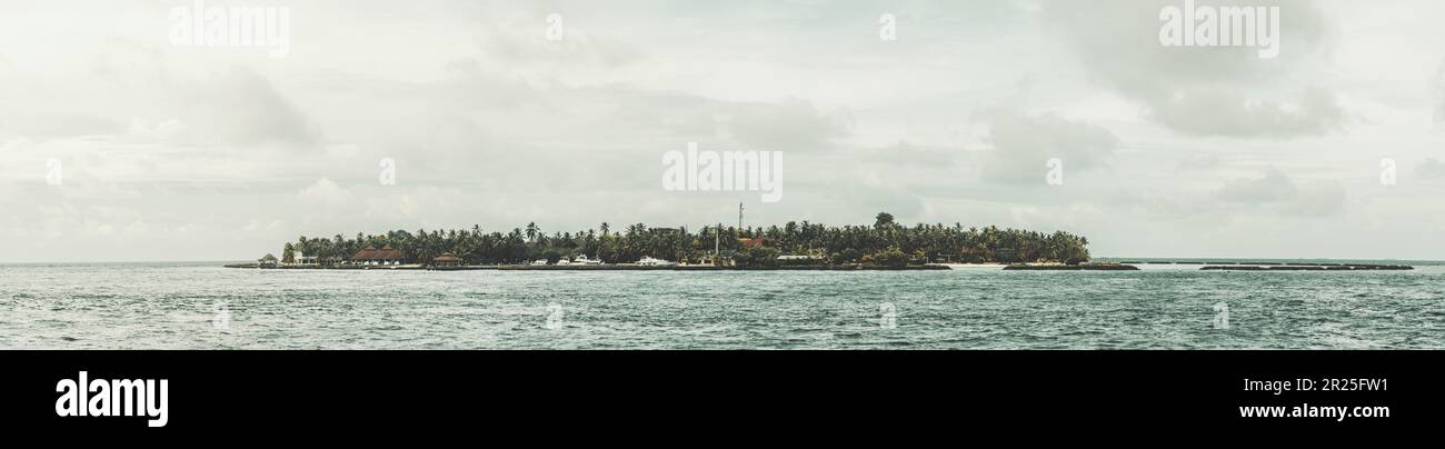 Maldives; Panorama of a Maldivian islet featuring lush green trees ...