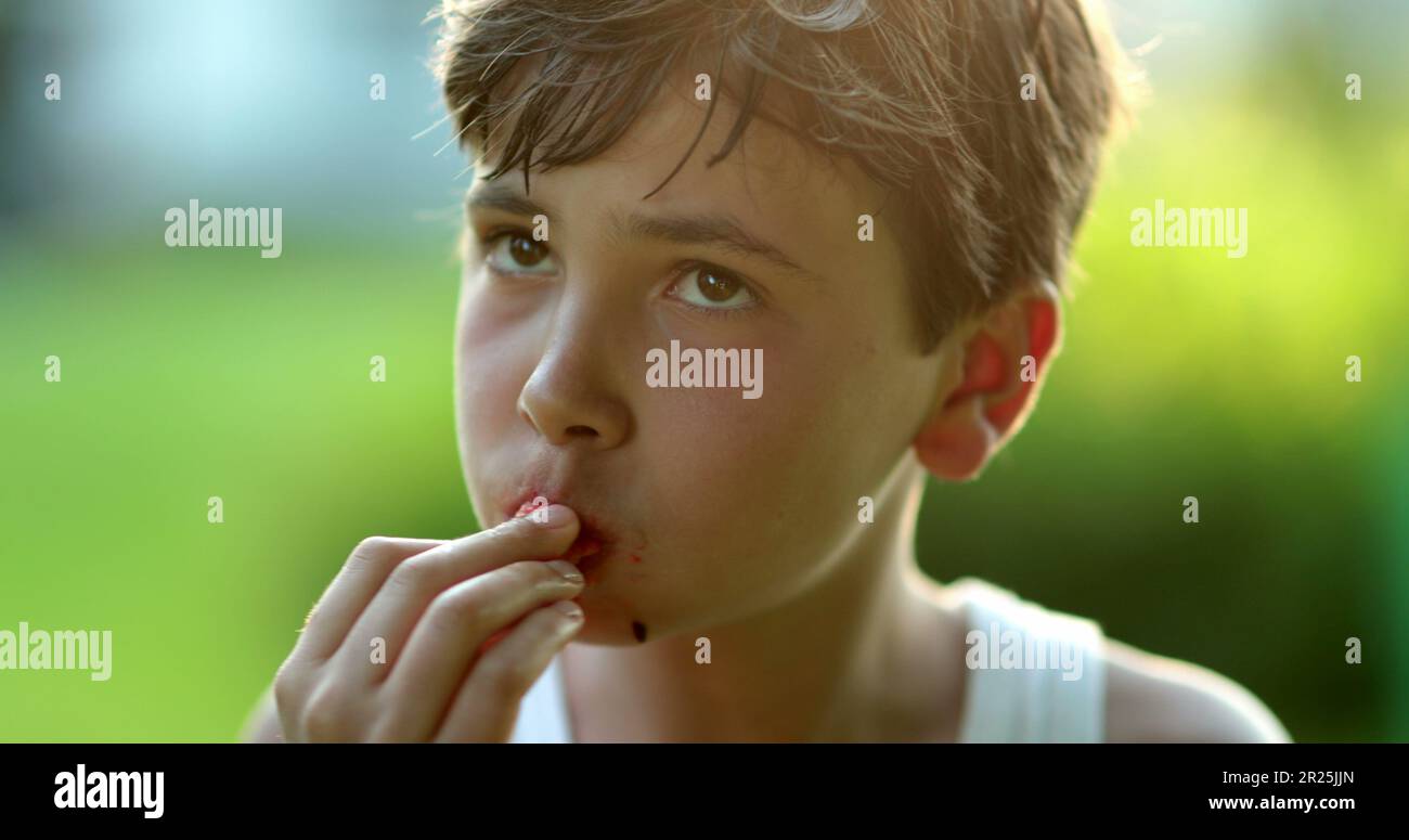 Young boy child eating healthy fruit snack outdoors during golden hour ...