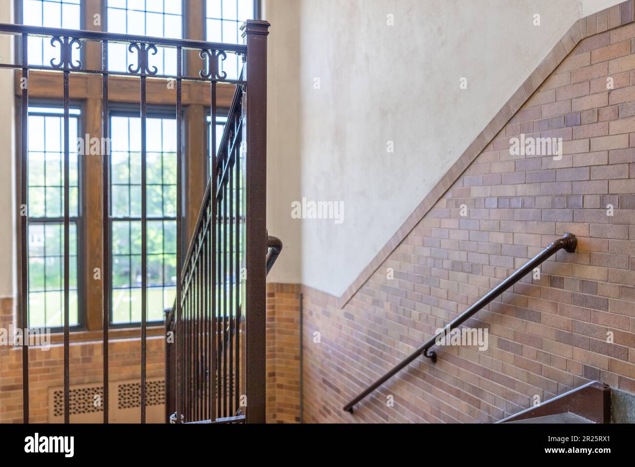 Nondescript stairway, hallway, with windows and brown railing, in a ...