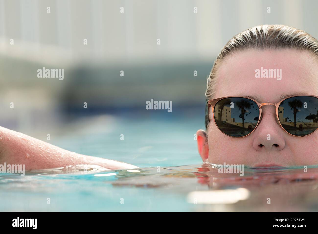 Lady in pool. , slicked back hair, water up to mouth wearing sunglasses ...