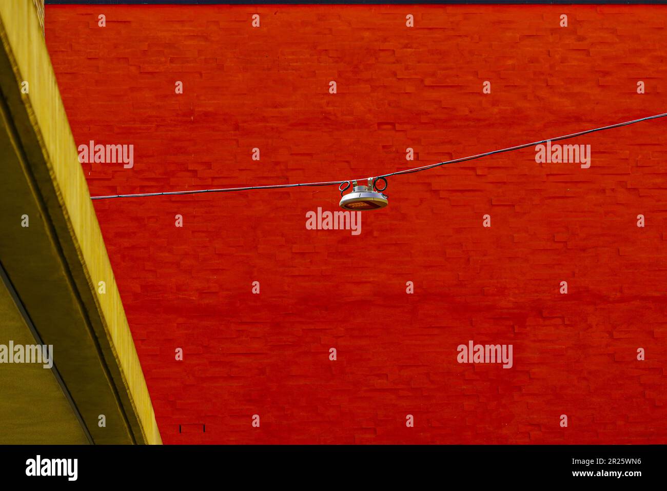 Two large outdoor halogen spotlights on ropes in front of a red house ...