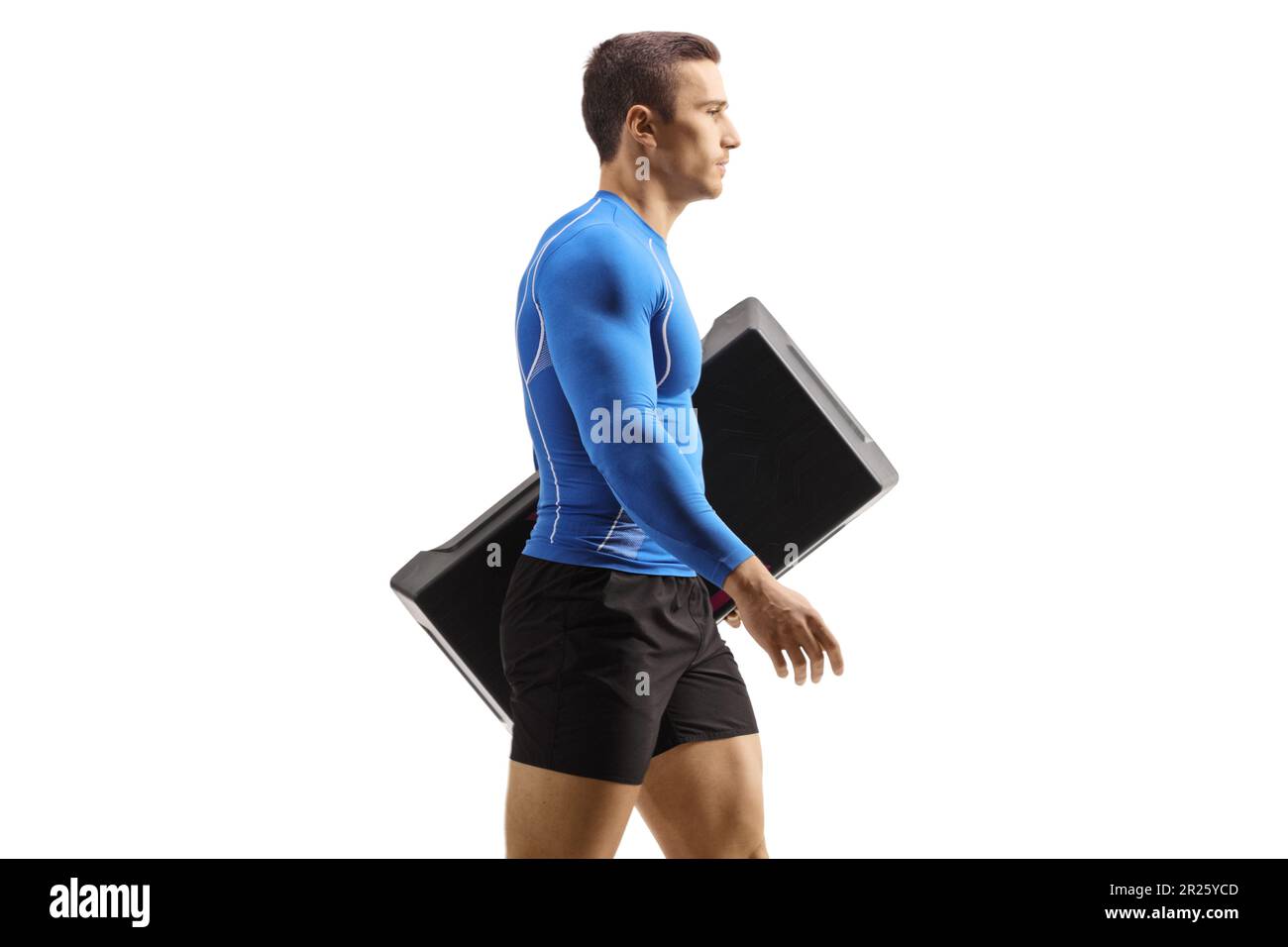 Profile shot of a fit man walking and carrying an aerobic stepper ...