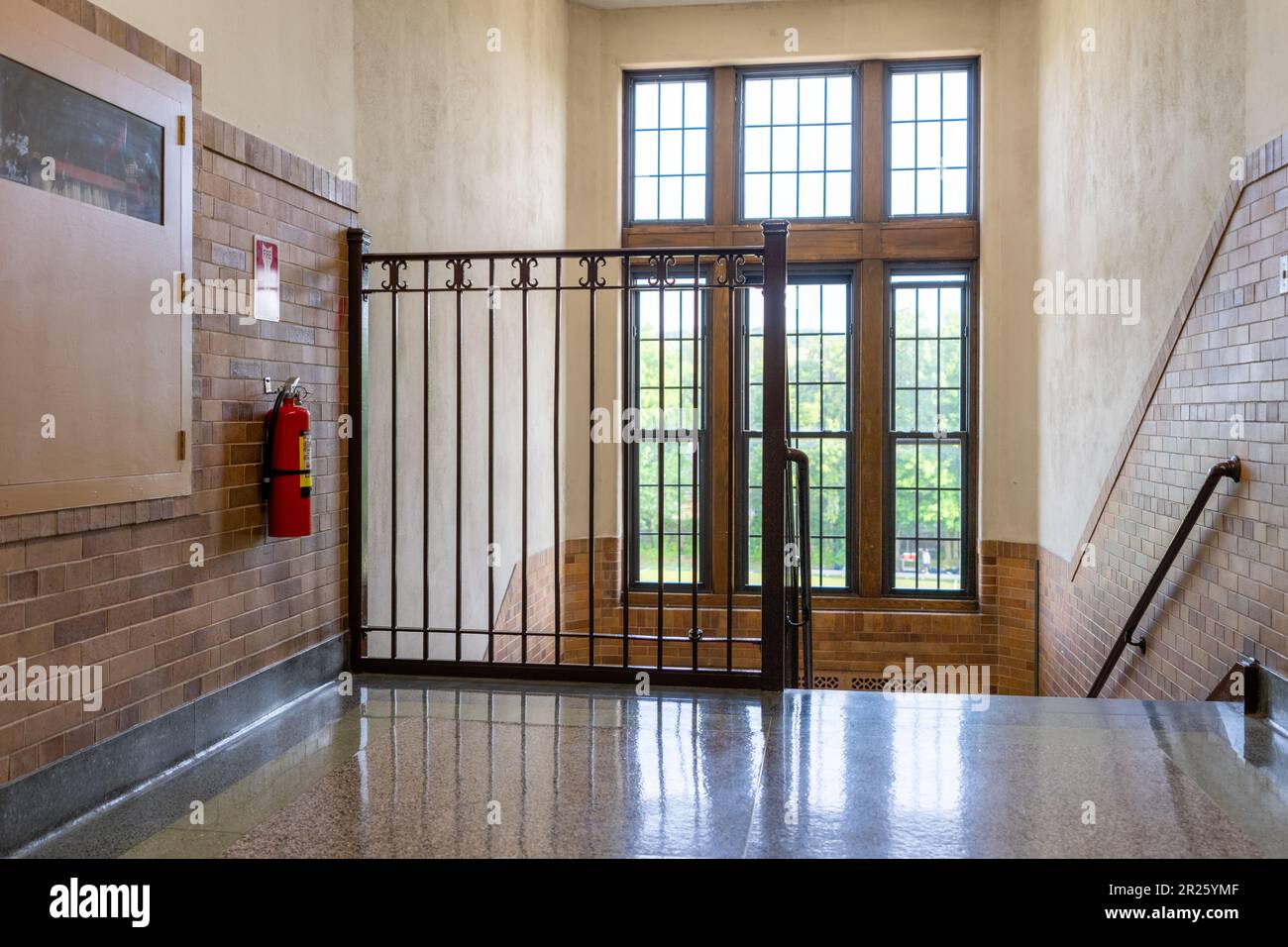 Nondescript stairway, hallway, with windows and brown railing, in a ...