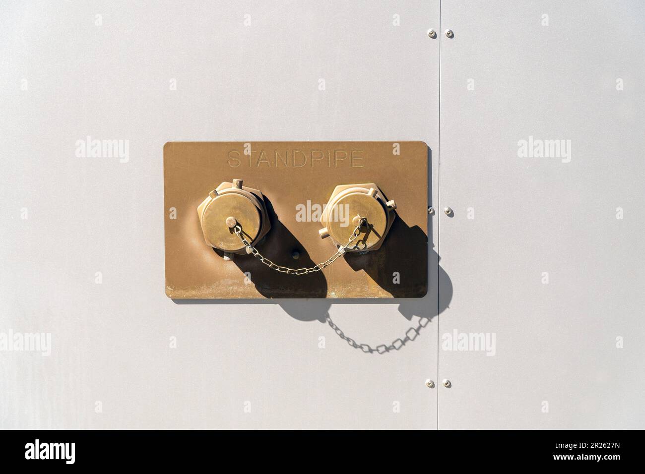 A brass weathered standpipe on a metal wall panel. Sunny day Stock ...