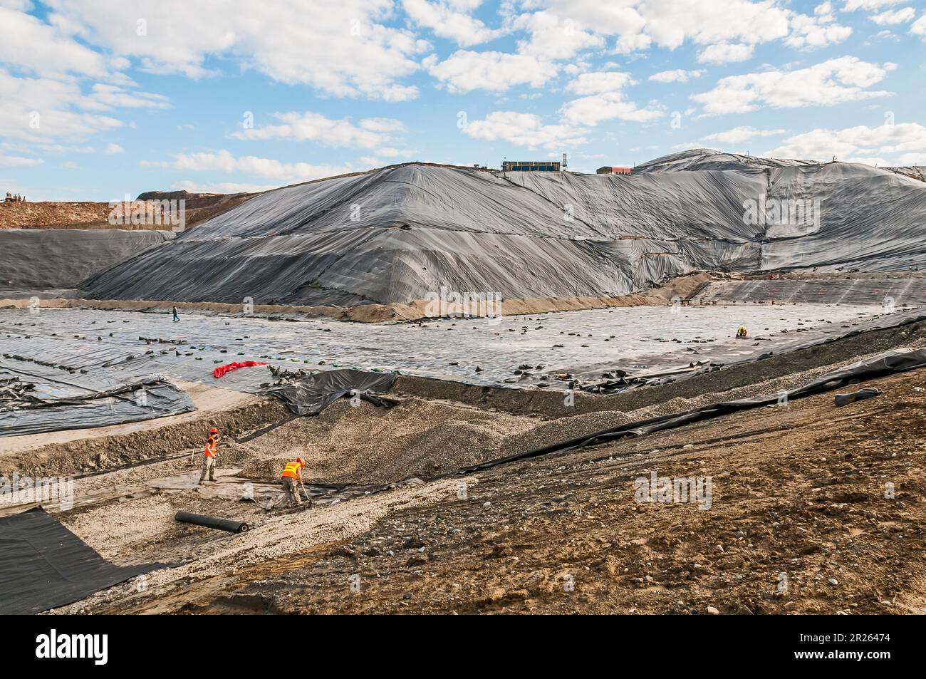 Five workers on geomembranes at an active landfill Stock Photo - Alamy