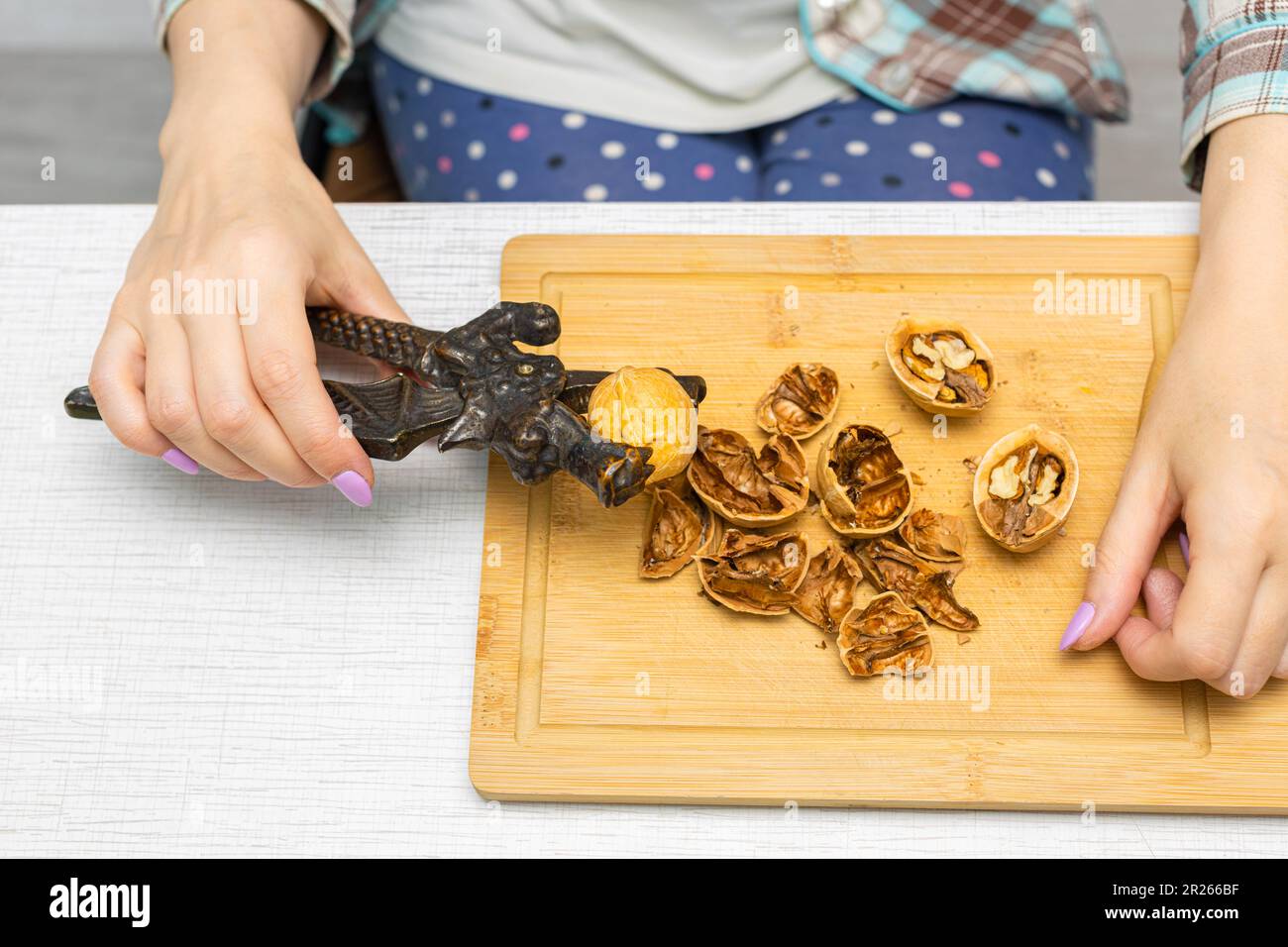woman cracking walnuts with a hand-held nutcracker. nut cracker for ...