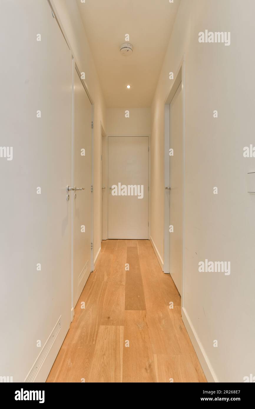 a long hallway with white walls and wood flooring on either side by ...