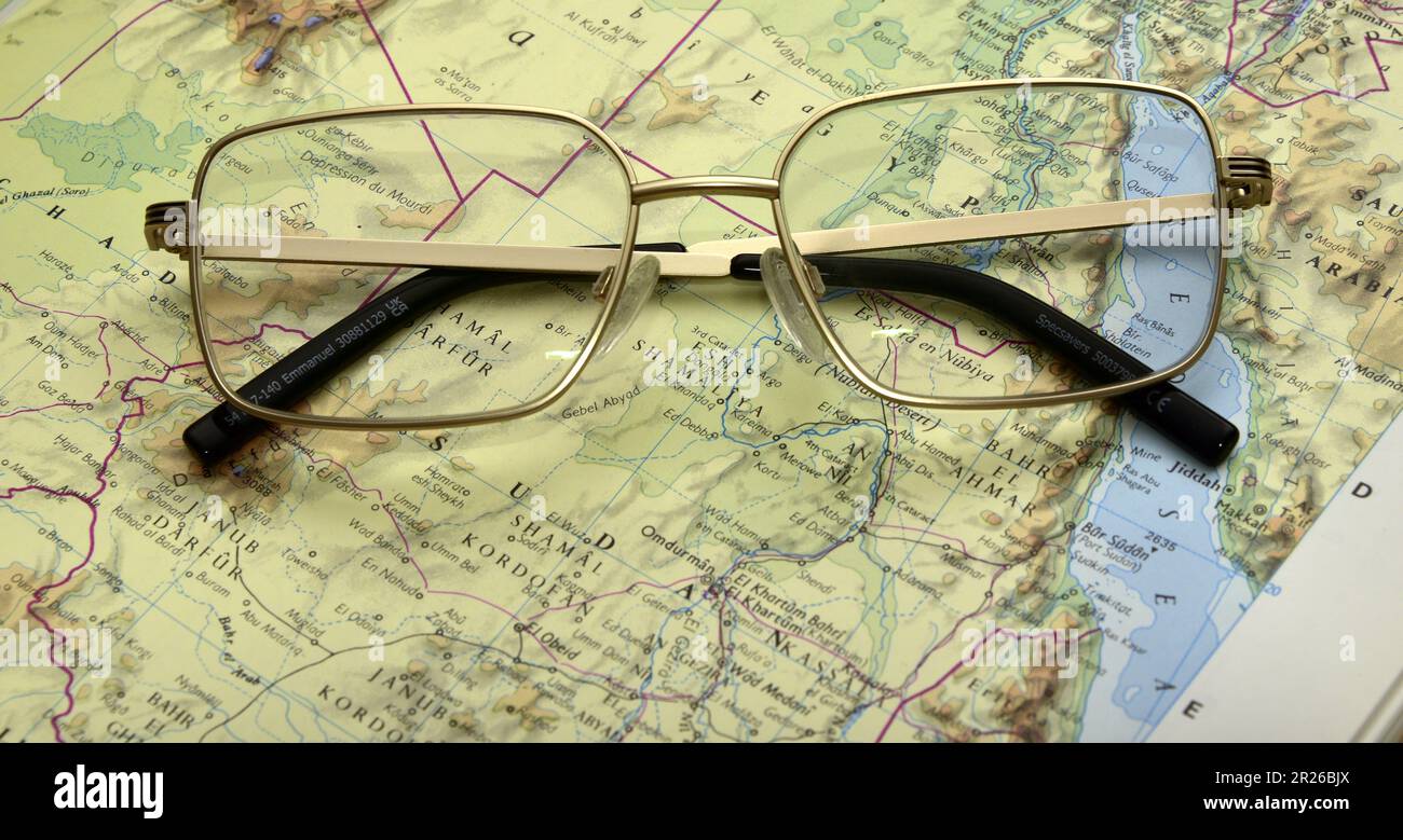 A pair of reading glasses or spectacles on an atlas or map showing part ...