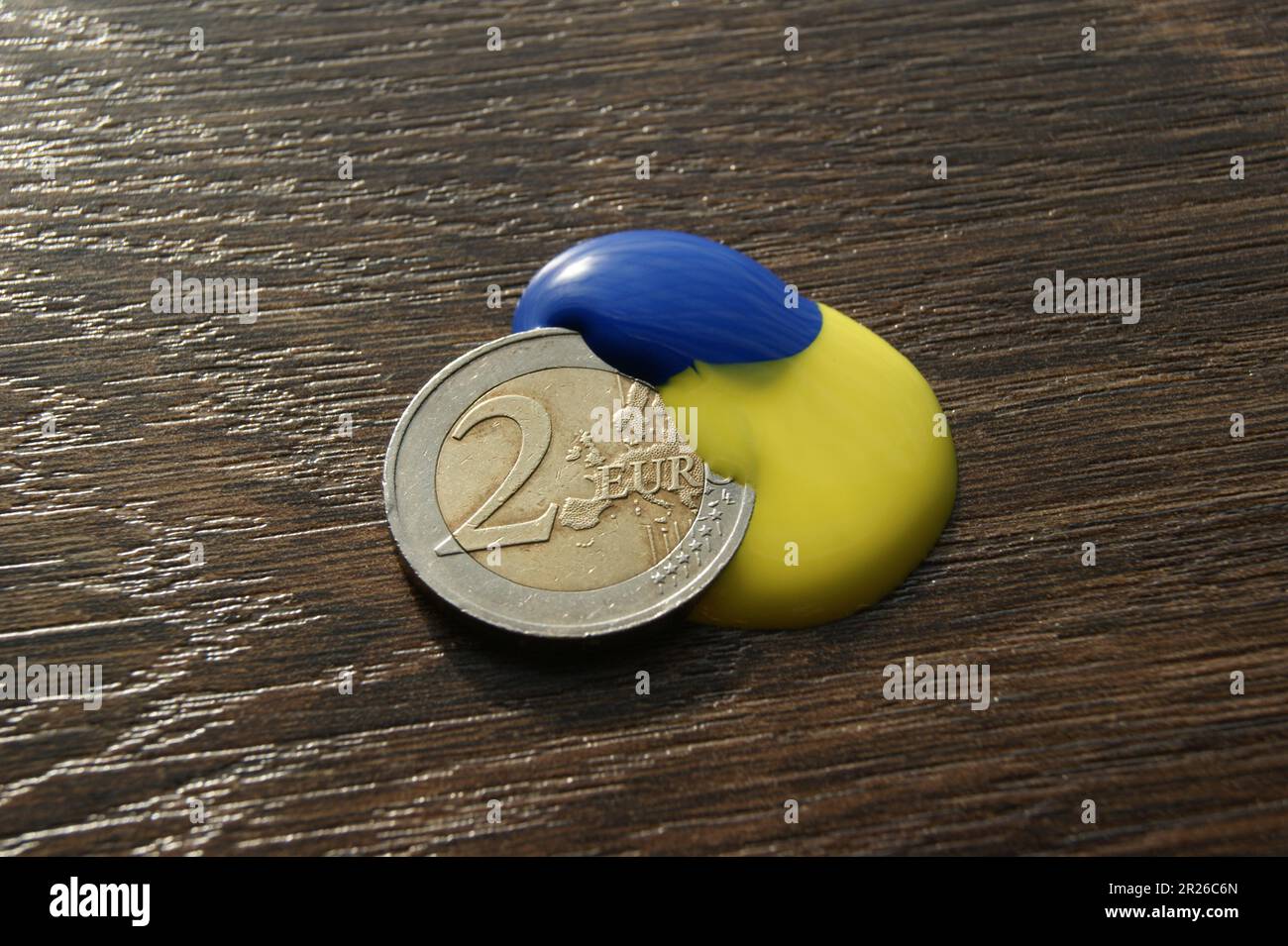 2 Euro coin on a dark wooden table. The colors of the Ukrainian flag on ...