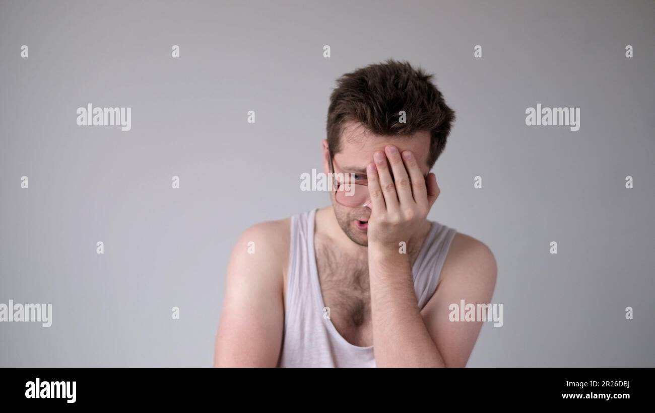 The tired European young man, lacking energy, closes his face with ...