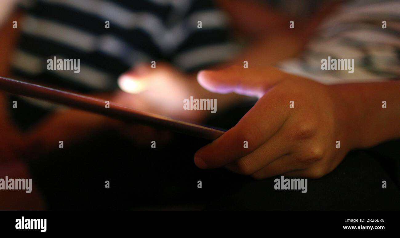 Child hands holding tablet device with screen glowing at night Stock ...