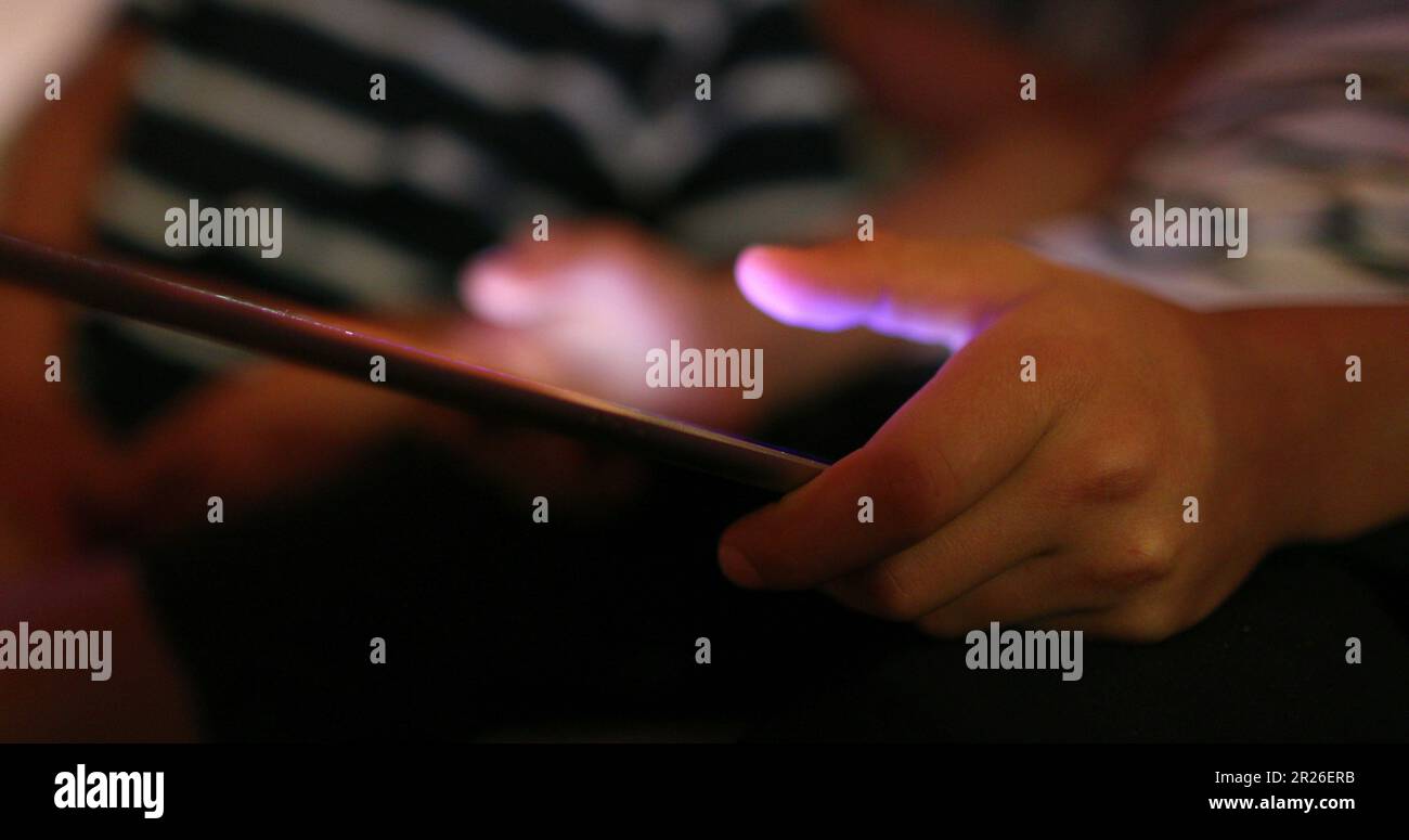 Child hands holding tablet device with screen glowing at night Stock ...