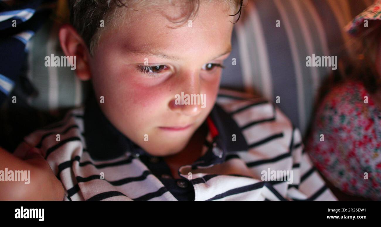Child using tablet device at night watching screen Stock Photo - Alamy