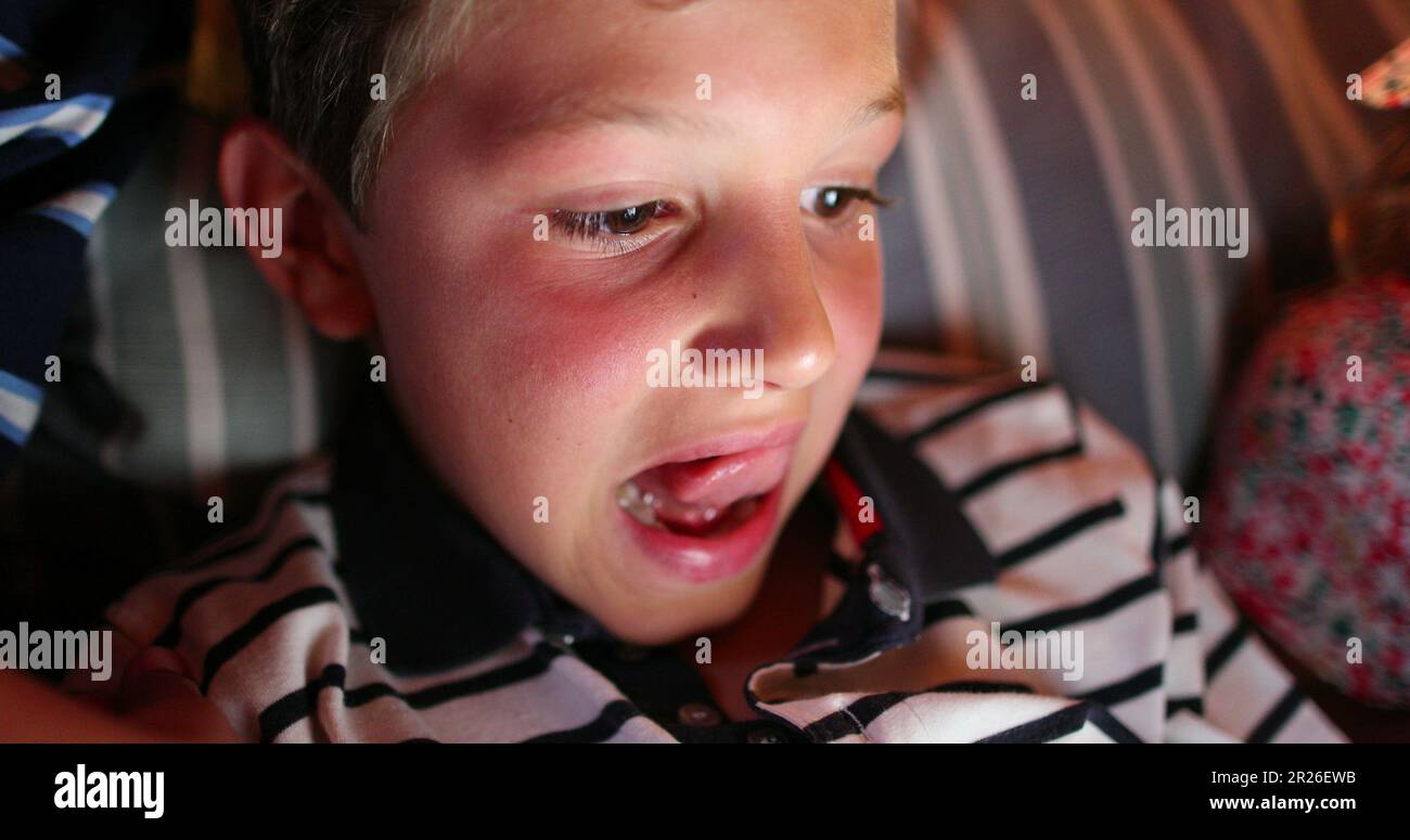 Child using tablet device at night watching screen Stock Photo - Alamy