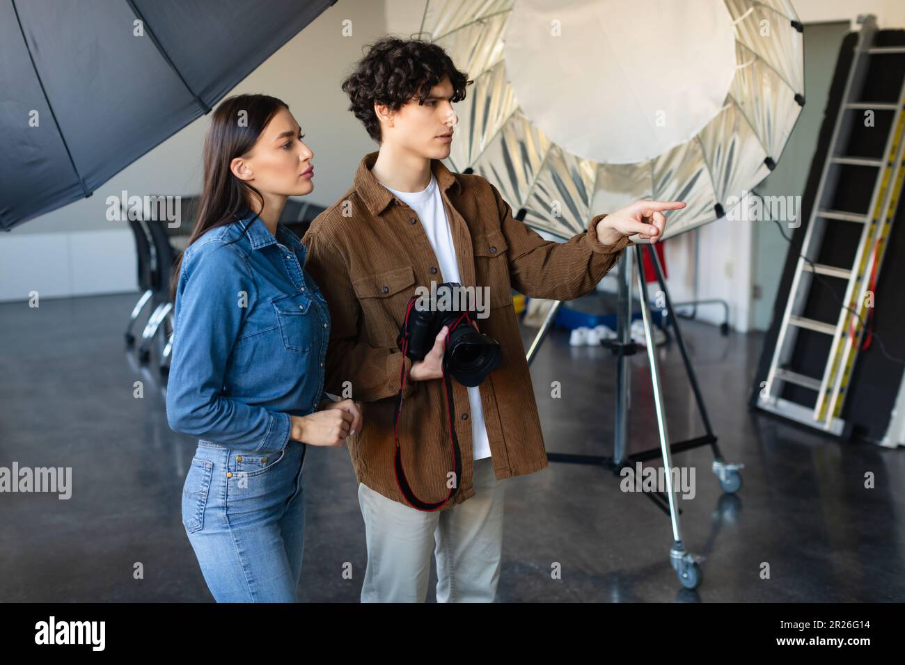 Behind the camera. Dynamic duo in modern photostudio preparing for ...