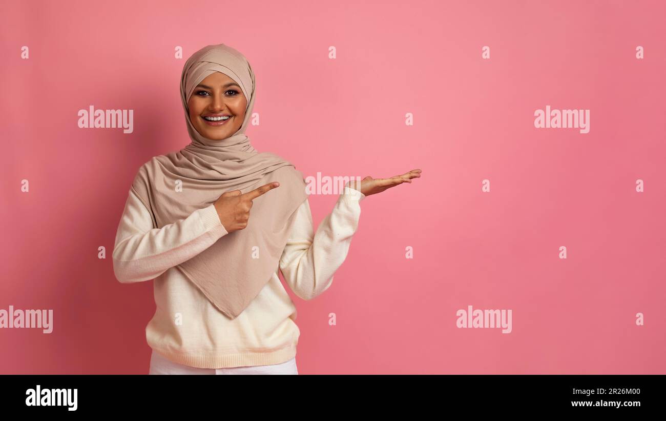 Excited Muslim Woman In Hijab Pointing At Invisible Object On Her Palm ...