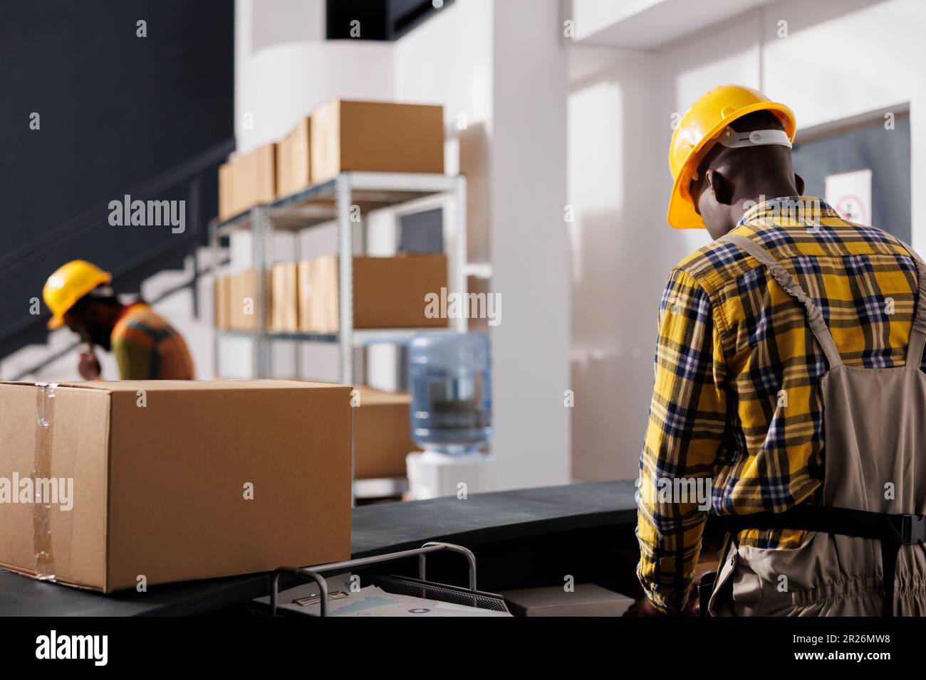Delivery service worker standing at reception, managing parcel ...