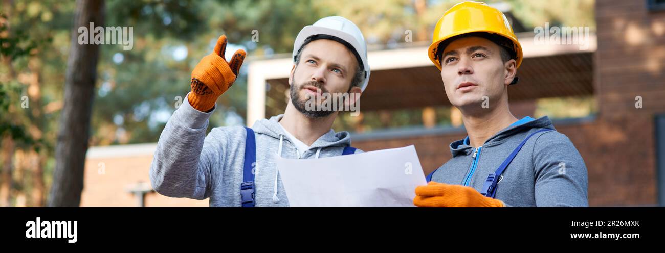 Building ideas. Portrait of two builders looking away while standing ...