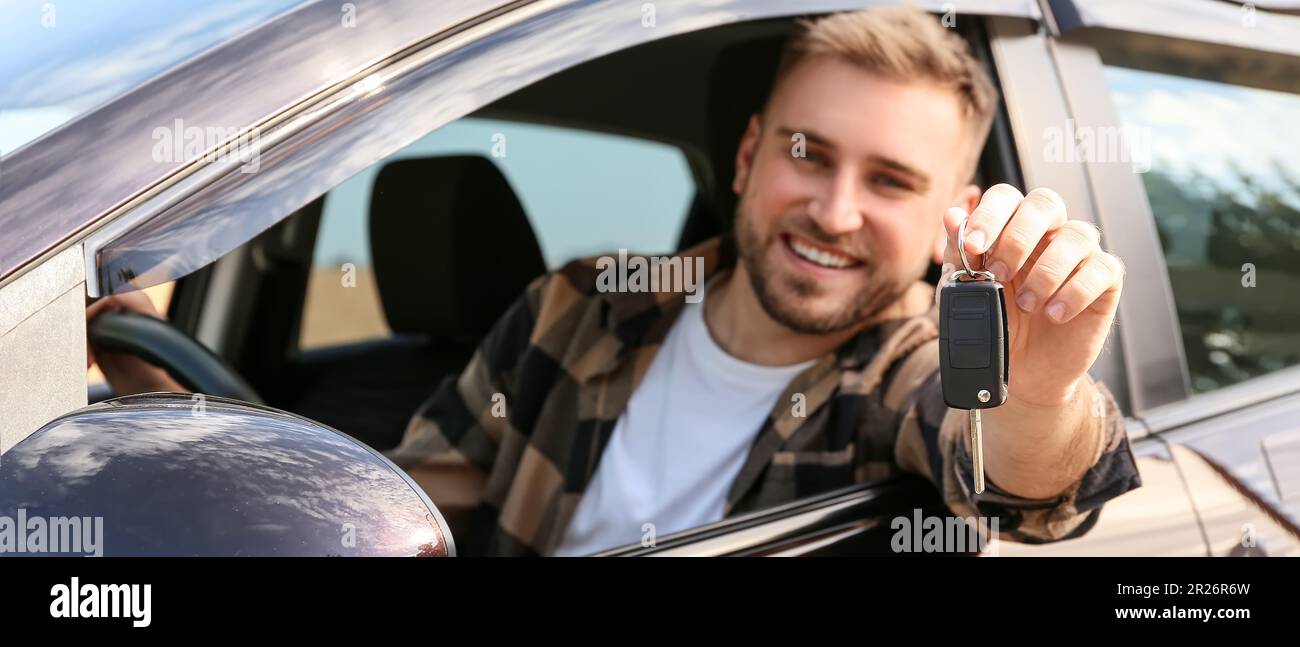 Happy young man with key sitting in his new car Stock Photo - Alamy