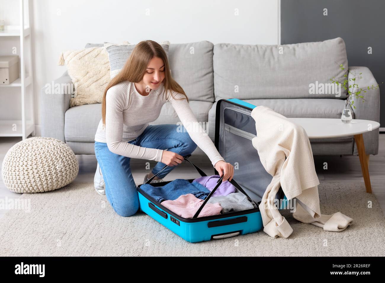 Young woman unpacking suitcase at home Stock Photo - Alamy