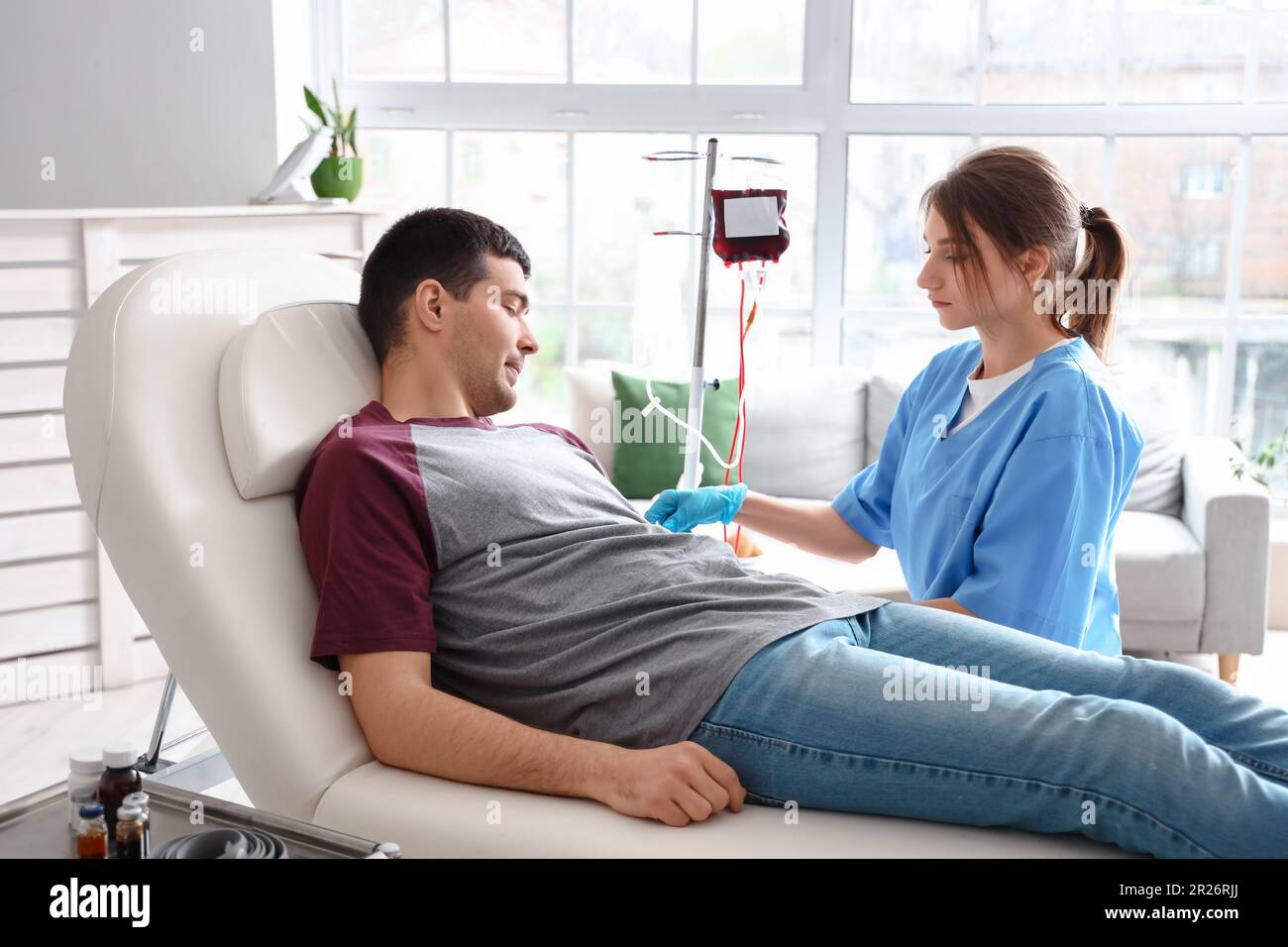 Female nurse taking blood from young donor in clinic Stock Photo - Alamy
