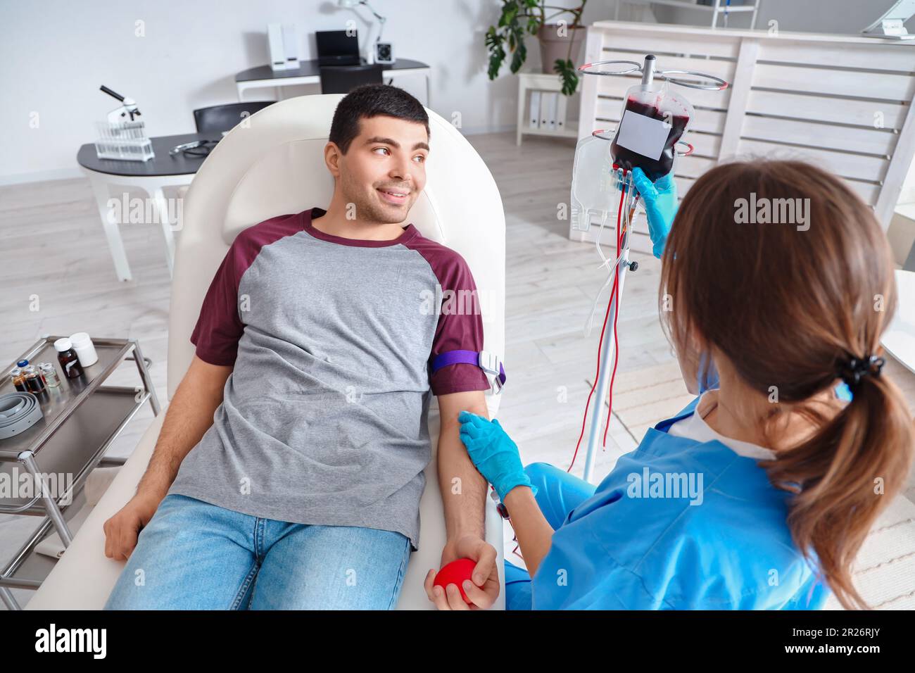 Female nurse taking blood from young donor in clinic Stock Photo - Alamy