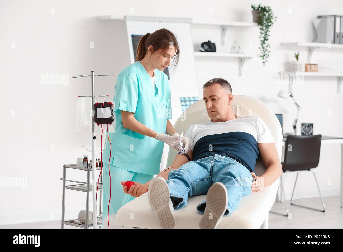 Female nurse taking blood from mature donor in clinic Stock Photo - Alamy