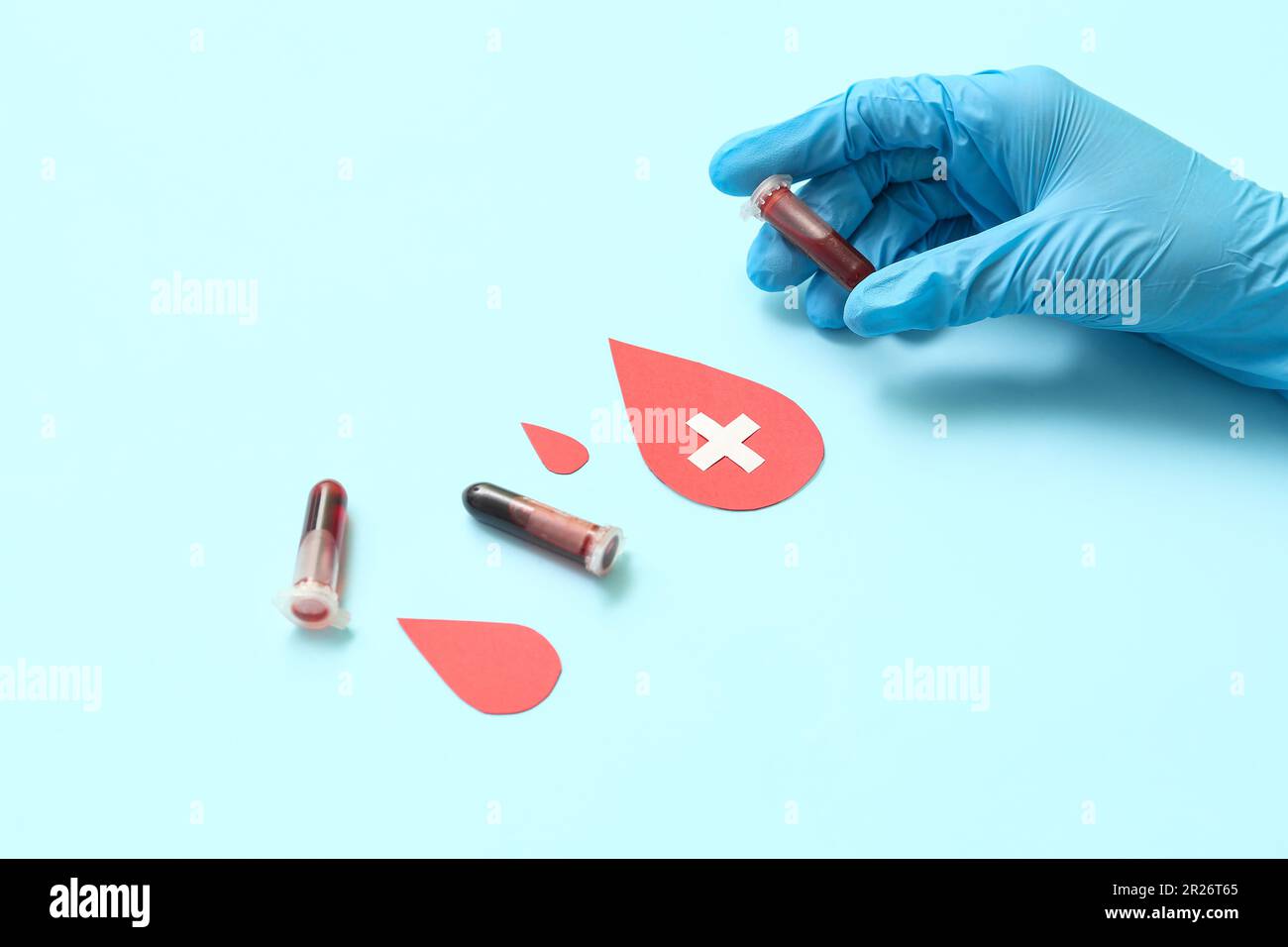 Female doctor with test tubes and paper blood drops on blue background ...