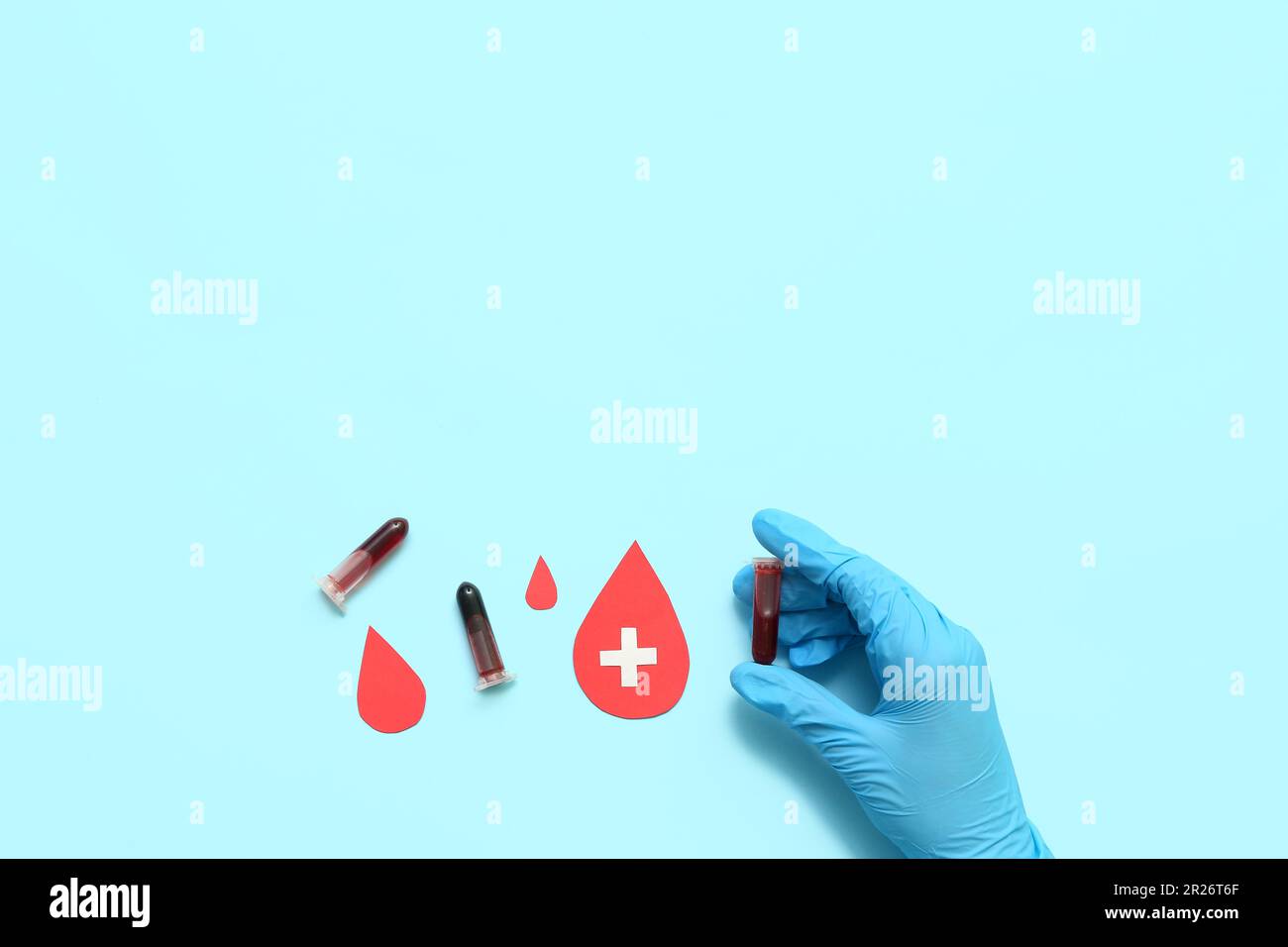 Female doctor with test tubes and paper blood drops on blue background ...