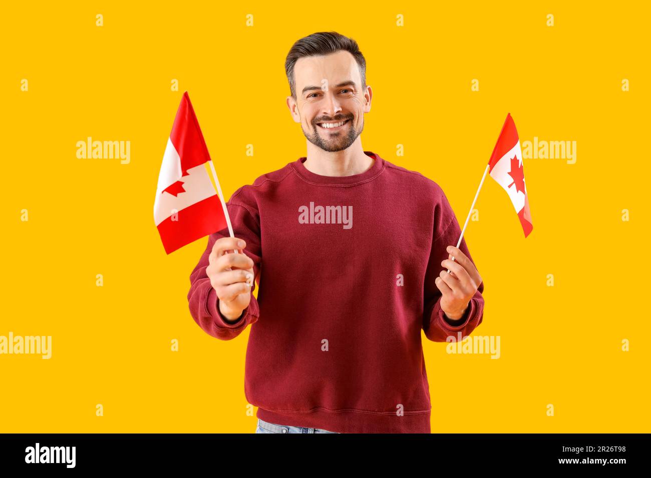 Handsome man with flags of Canada on yellow background Stock Photo - Alamy