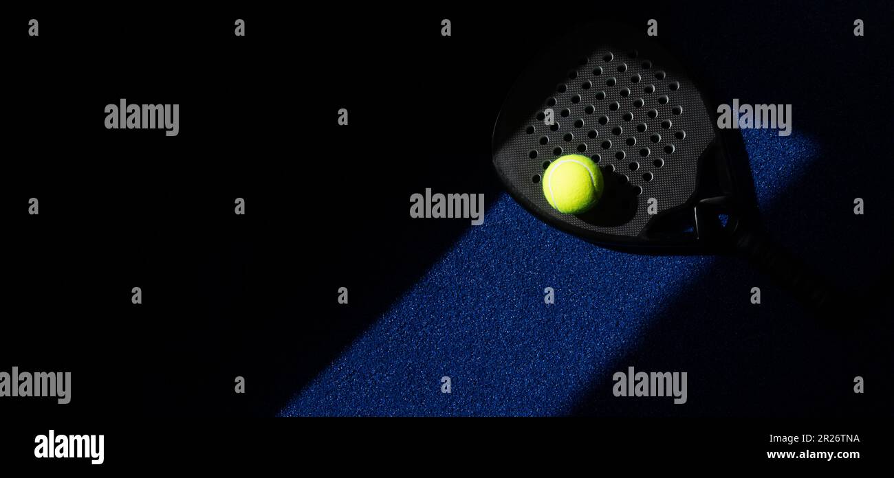 Black professional paddle tennis racket and ball with natural lighting ...