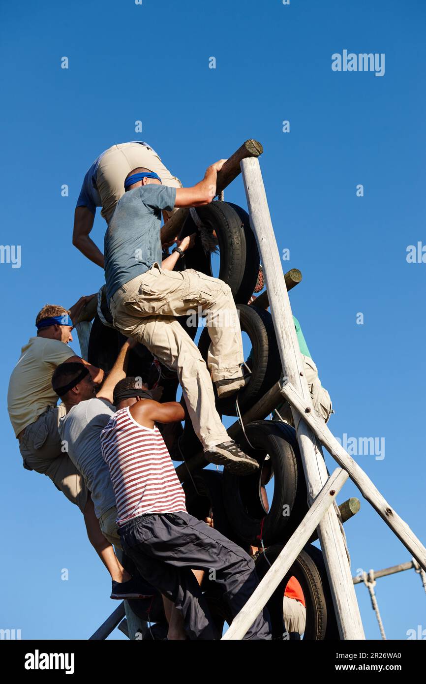 Once more unto the breach...a group of men climbing over an obstacle at ...