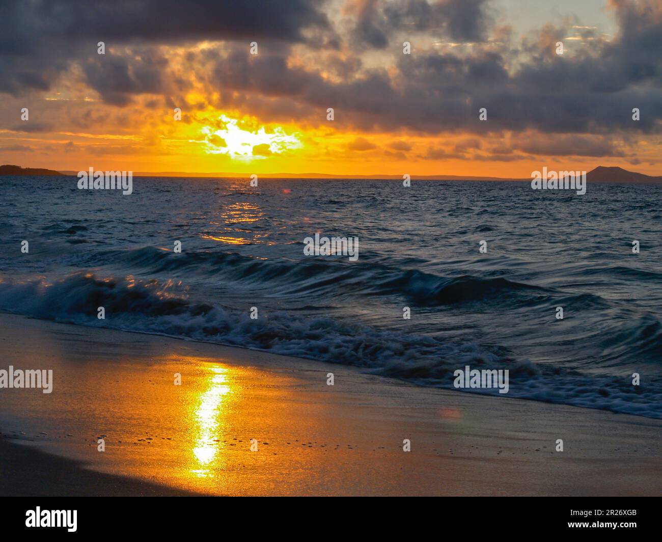 Intense glow of setting sun through dark dramatic clouds over horizon ...