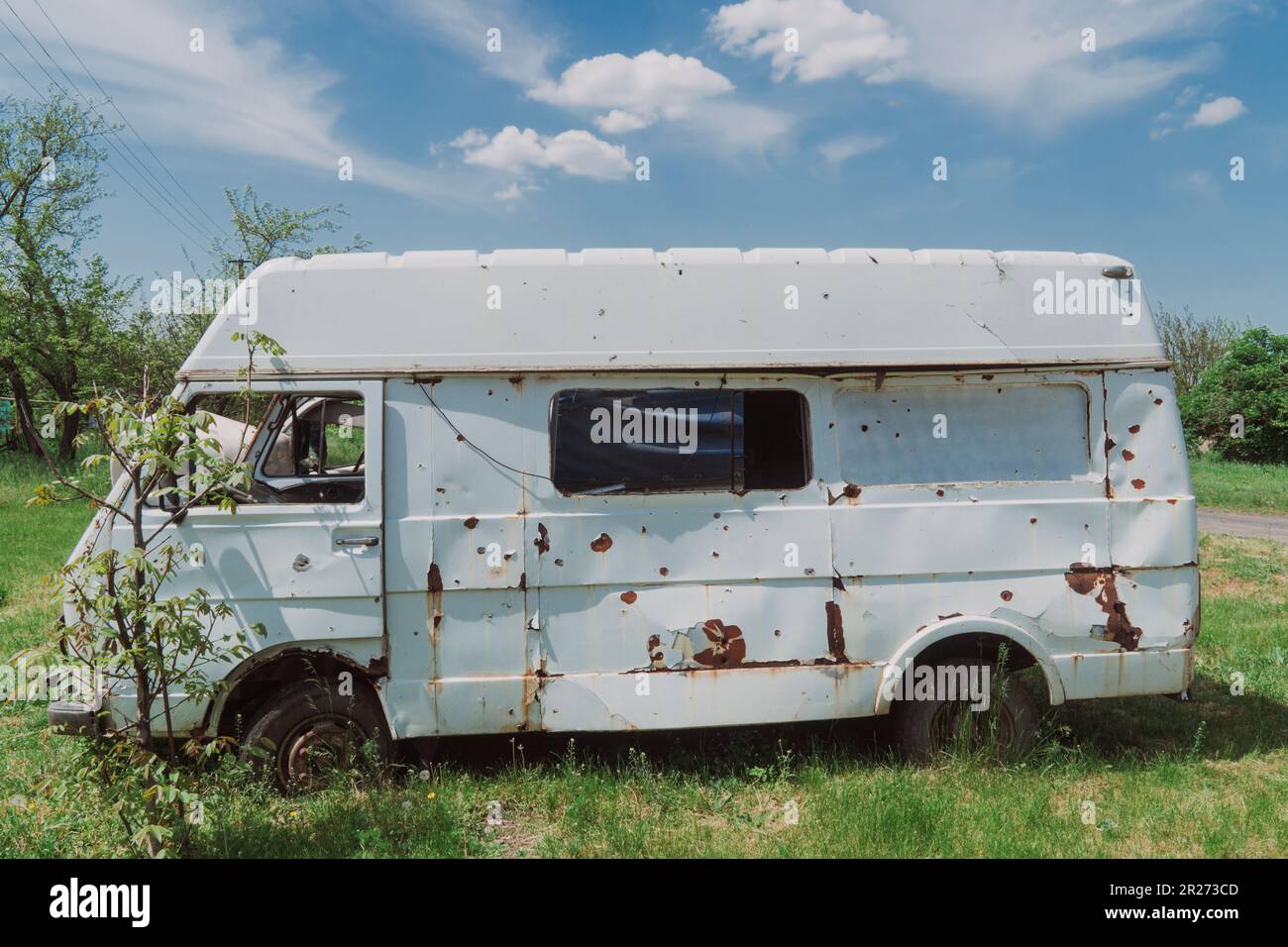 An old bus in the countryside, damaged by artillery fire. War in ...