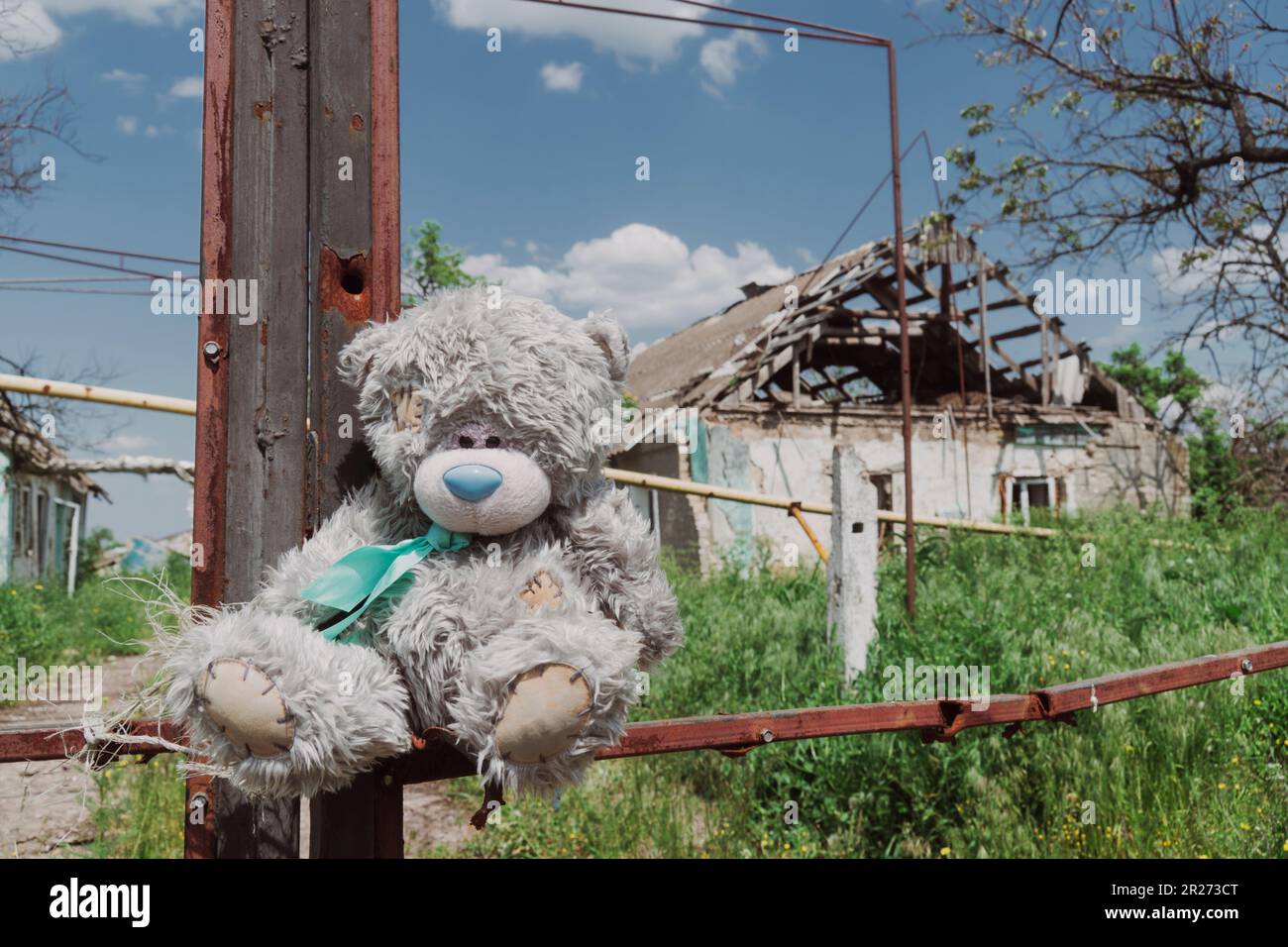Countryside. A toy (teddy bear) in front of a house destroyed by ...